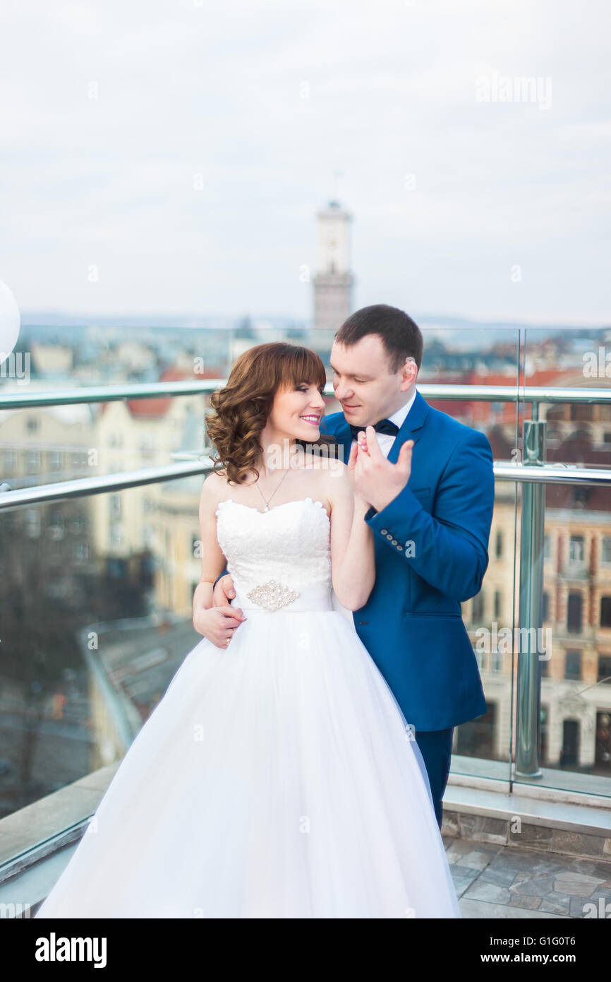 Groom hugging from back bride going for kiss standing on the terrace ...