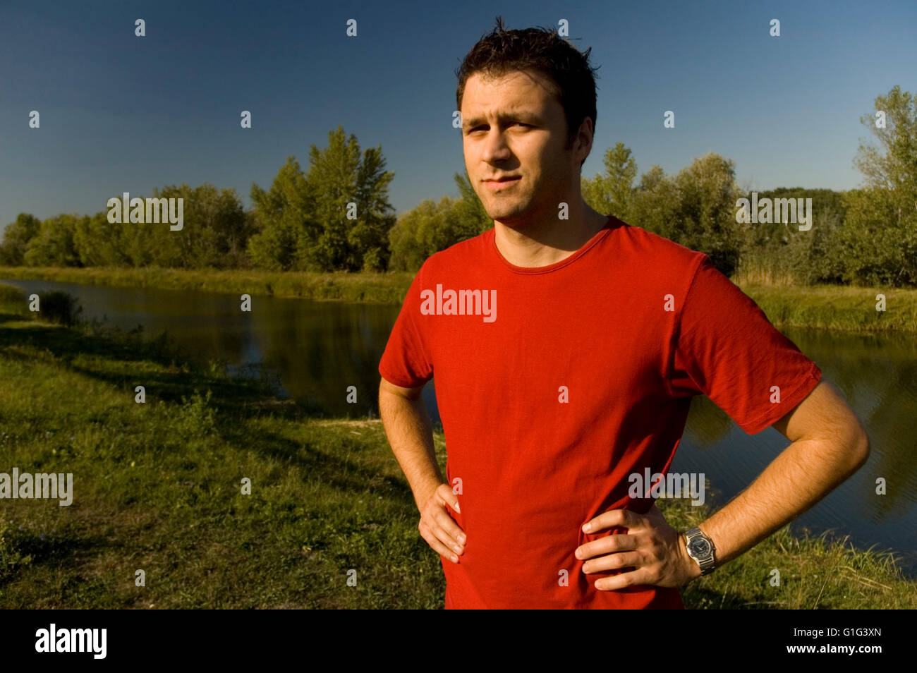 Young man with red t-shirt standing at the river Stock Photo - Alamy