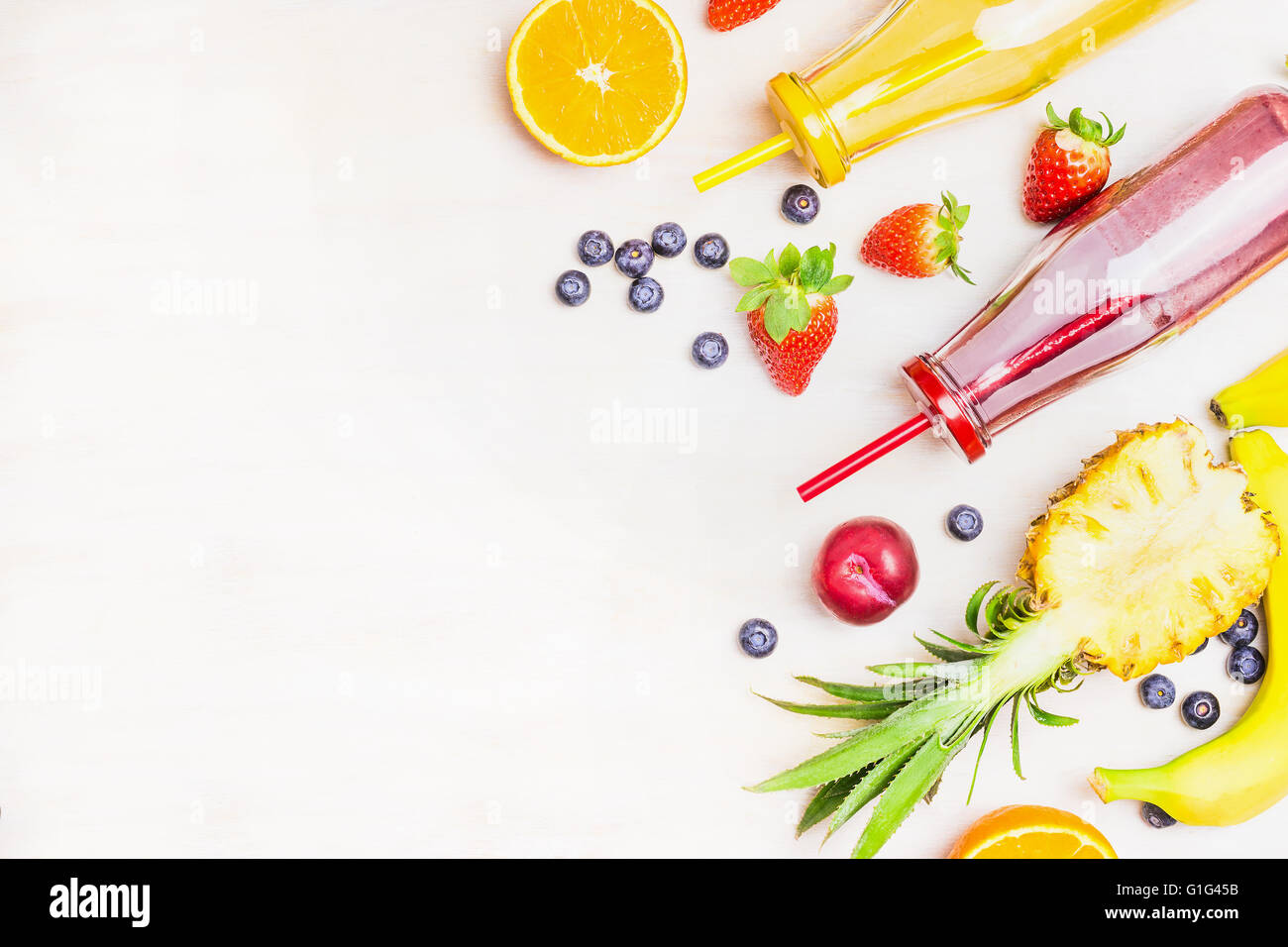 Red and yellow smoothies in bottles with fruits ingredients on white ...
