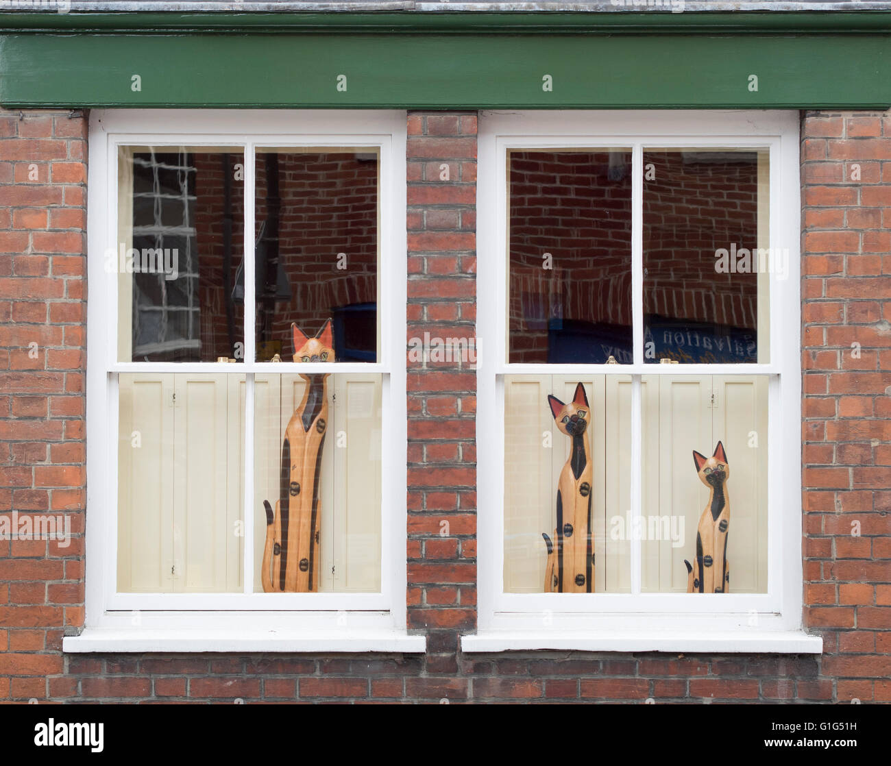 Pretty wooden ornamental cats on display in a window Stock Photo - Alamy