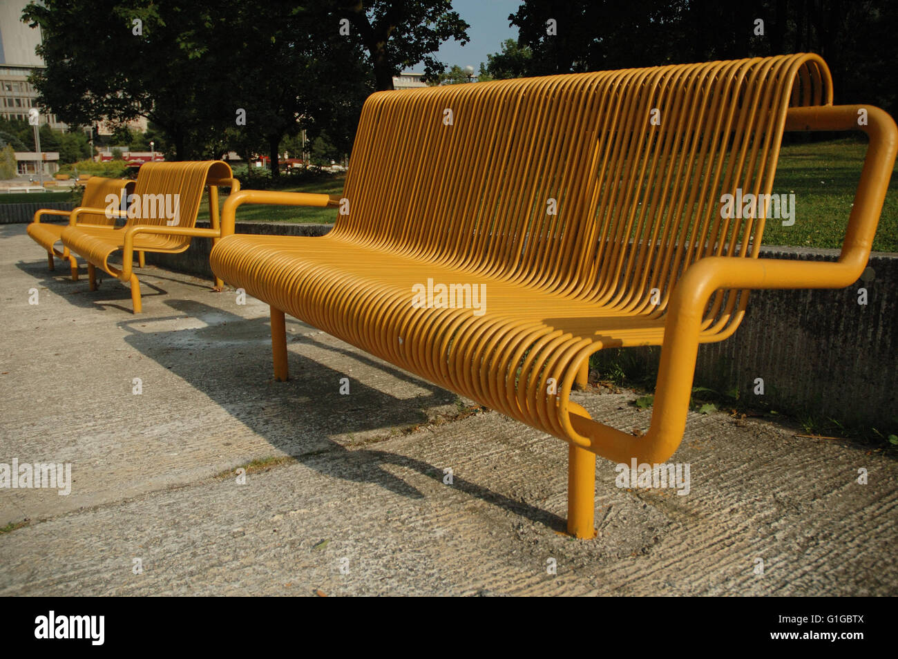 Yellow retro styled benches in the city parc Stock Photo - Alamy