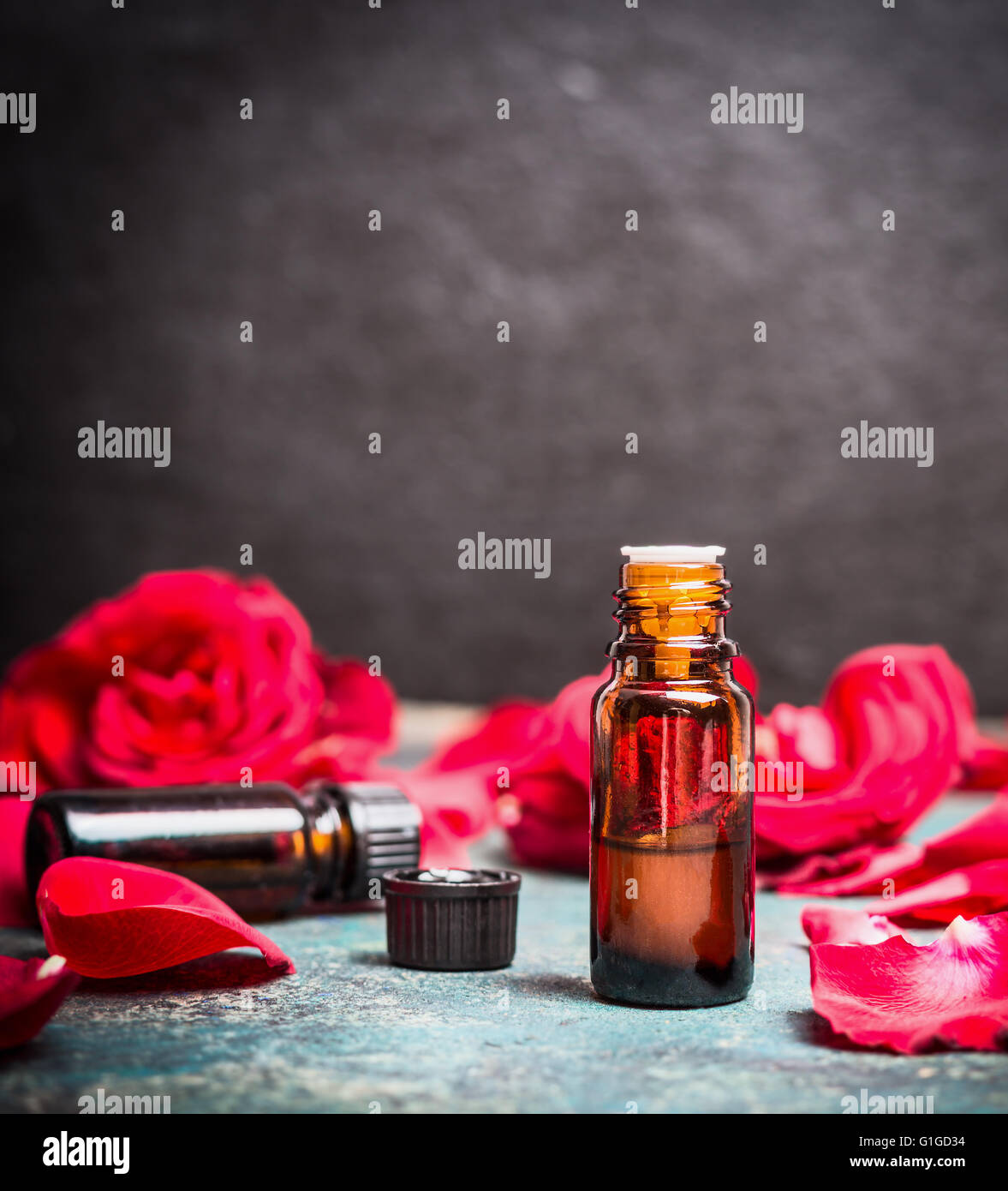 Bottle of roses essential oil and petals of red roses , side view ...