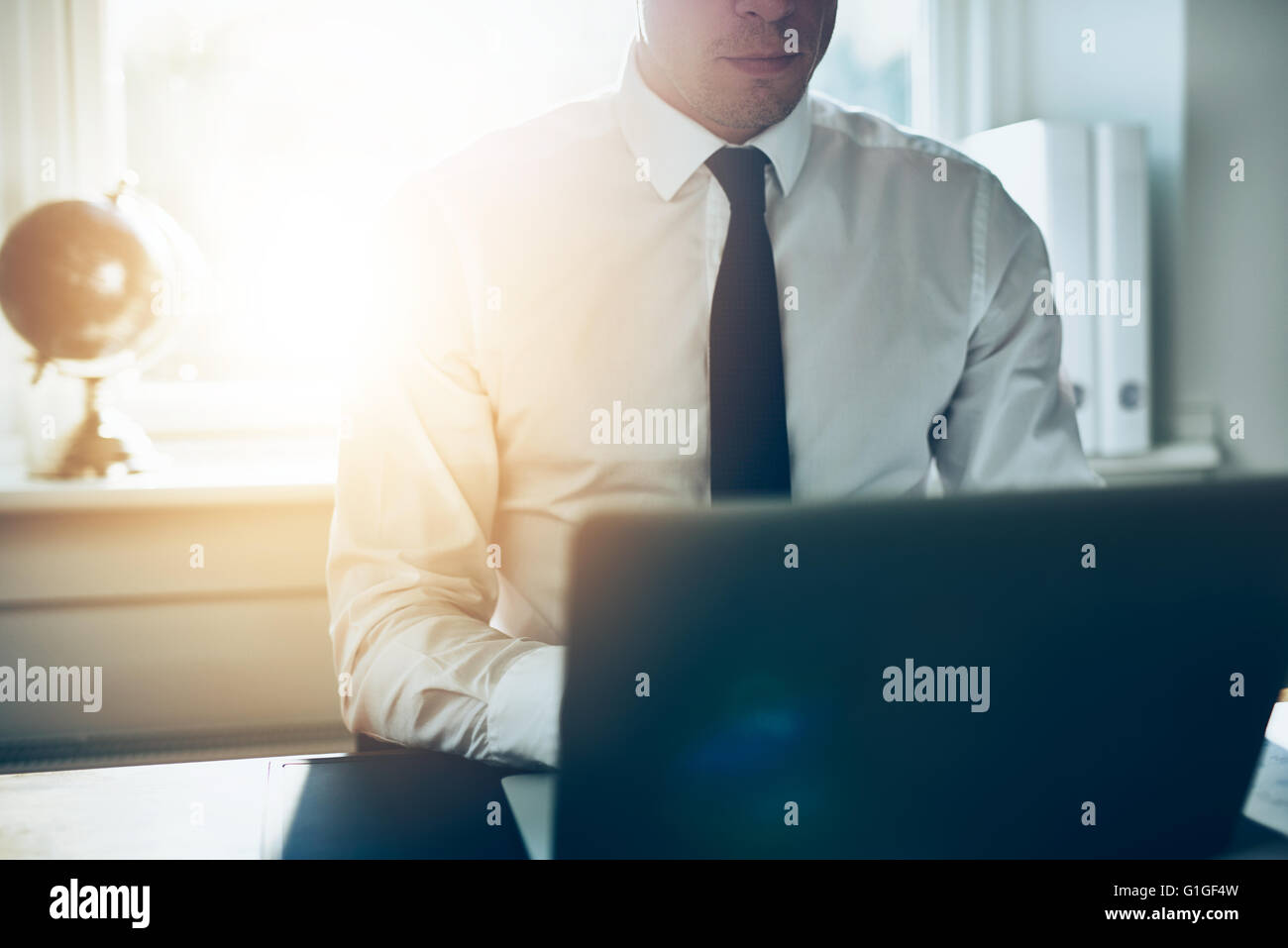Close up of business man working at laptop, white shirt and tie ...