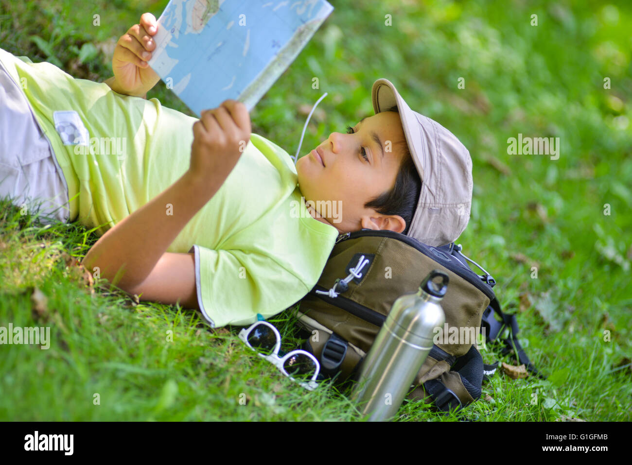 Young boy lying in the grass looking at a map Stock Photo - Alamy