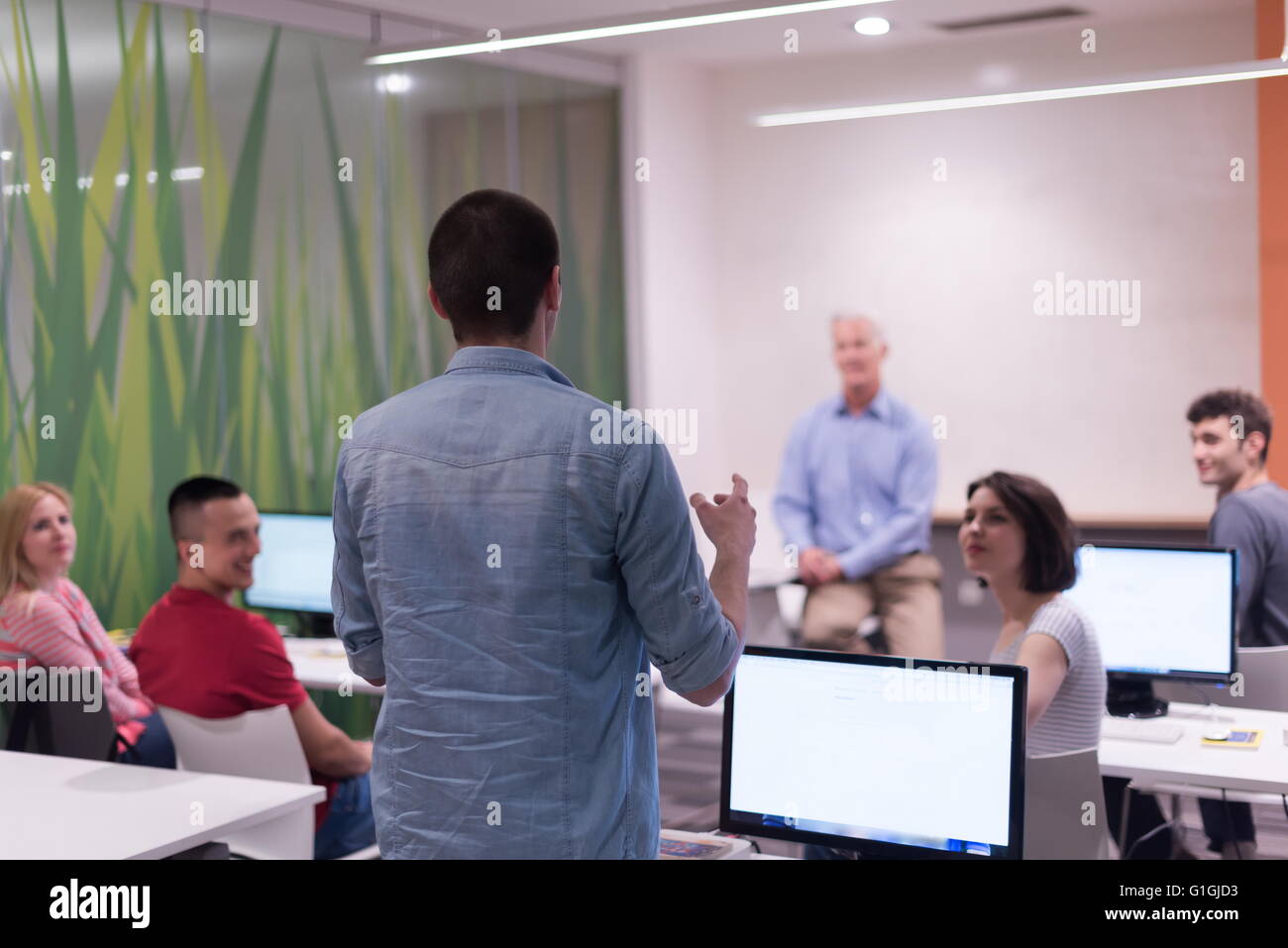 student answering a question in classroom, mature teacher and students ...