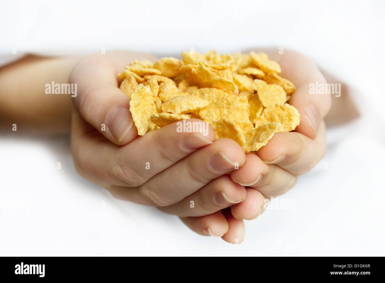 Little girl holds a handful of cereal isolated on white on white ...