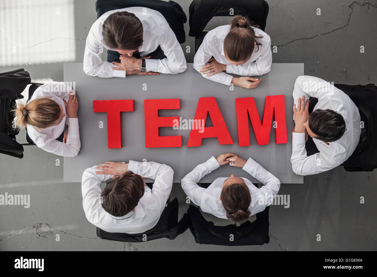 Business people sitting around the table with red letters TEAM ...