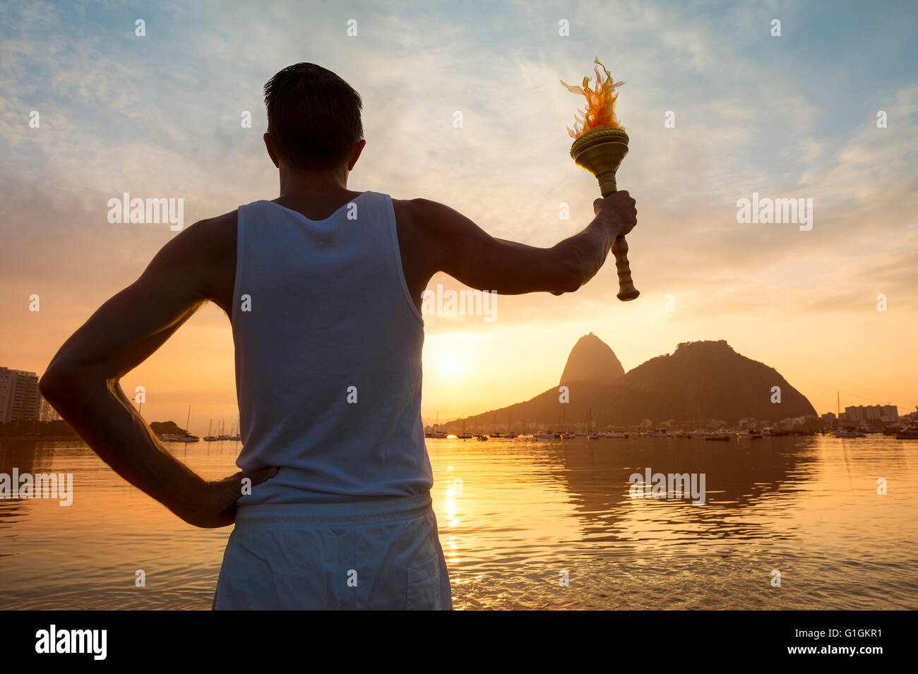 Athlete standing with sport torch against a scenic sunrise view of ...