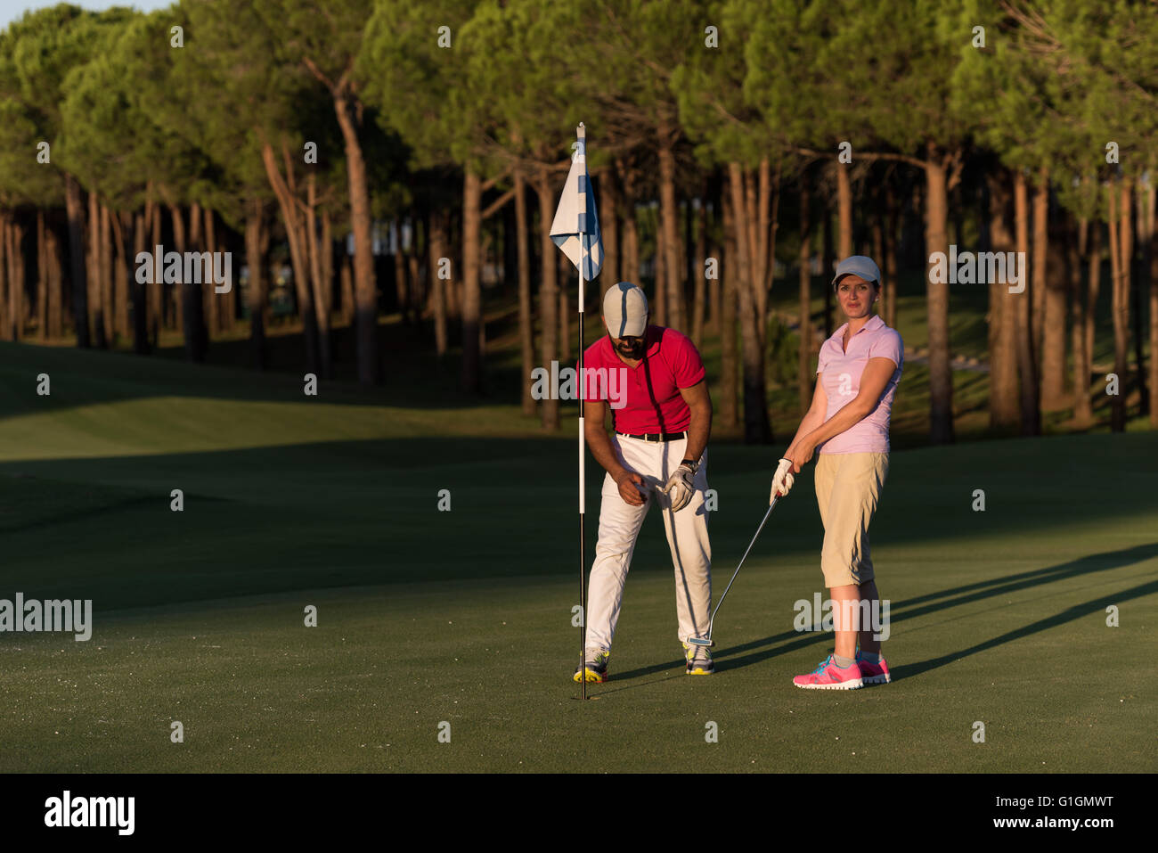 male golf instructor teaching female golf player, personal trainer ...