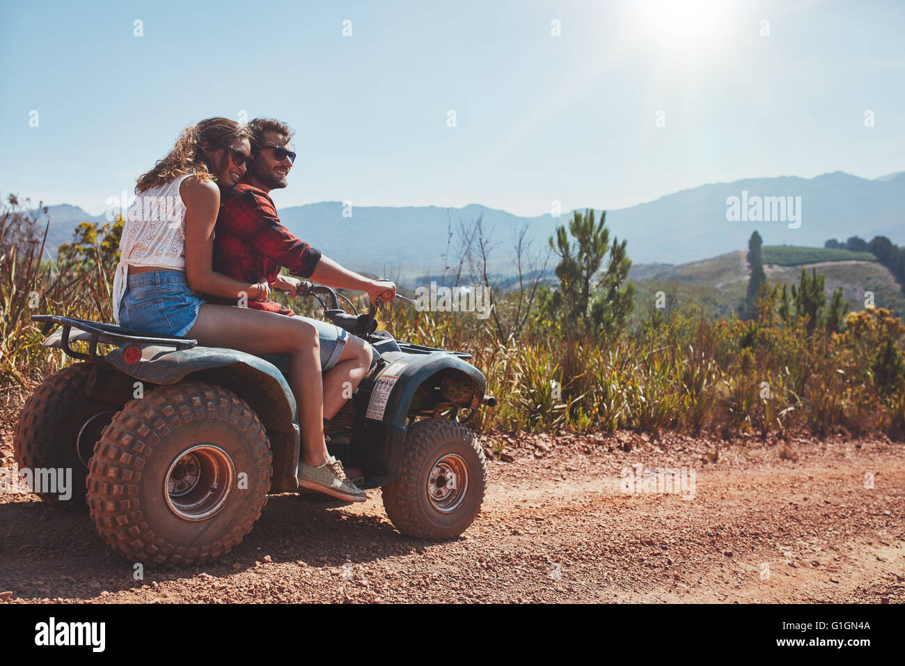 Happy young couple in nature on a quad bike. Young man and woman ...