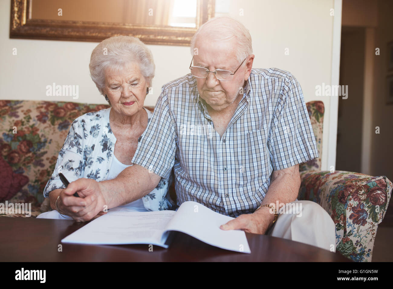 Portrait of a retired couple looking over documents while sitting at ...