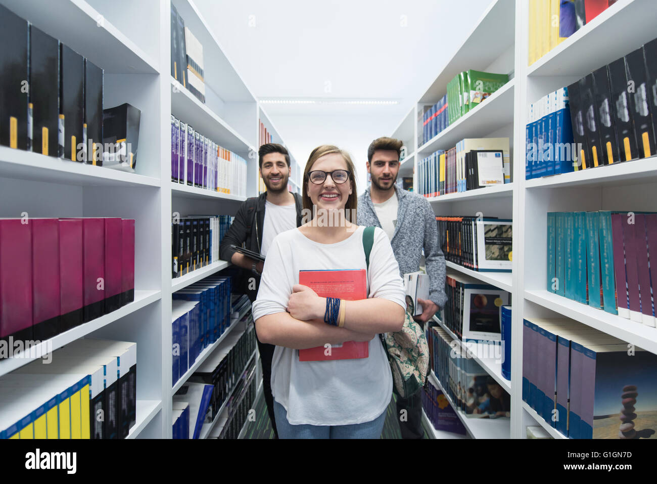 happy students group in school library selecting books to read and ...