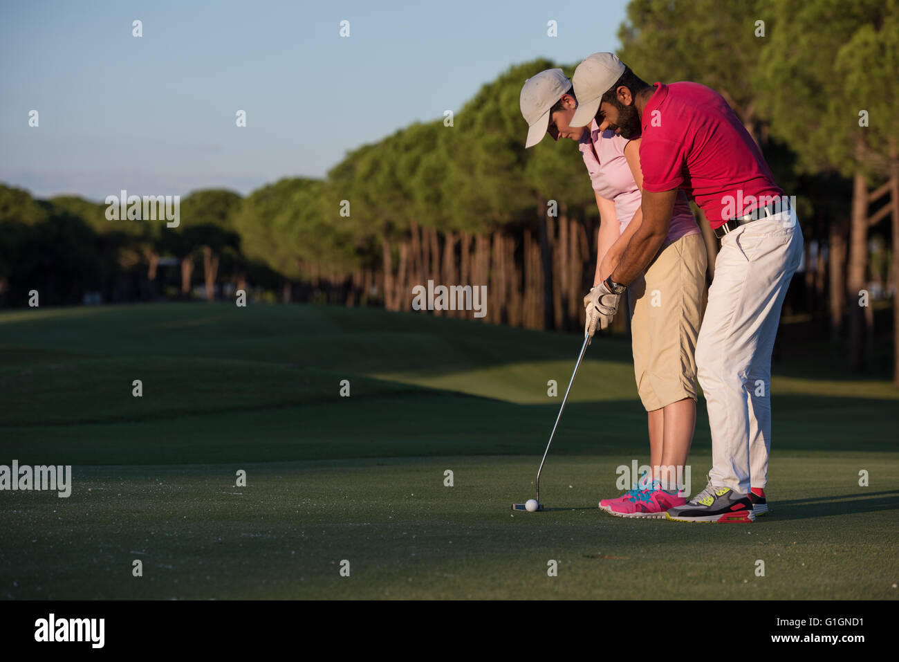 male golf instructor teaching female golf player, personal trainer ...