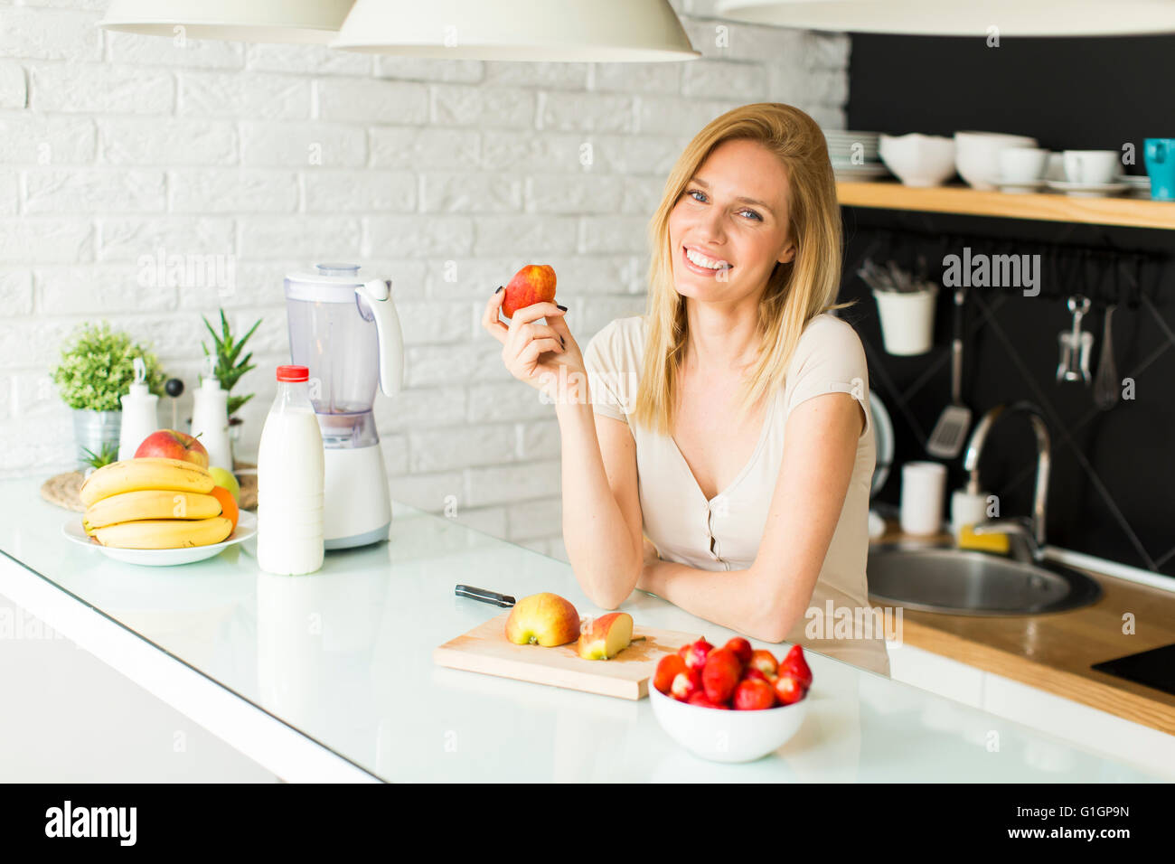 Pretty young woman preparing fruits in the modern kitchen Stock Photo ...