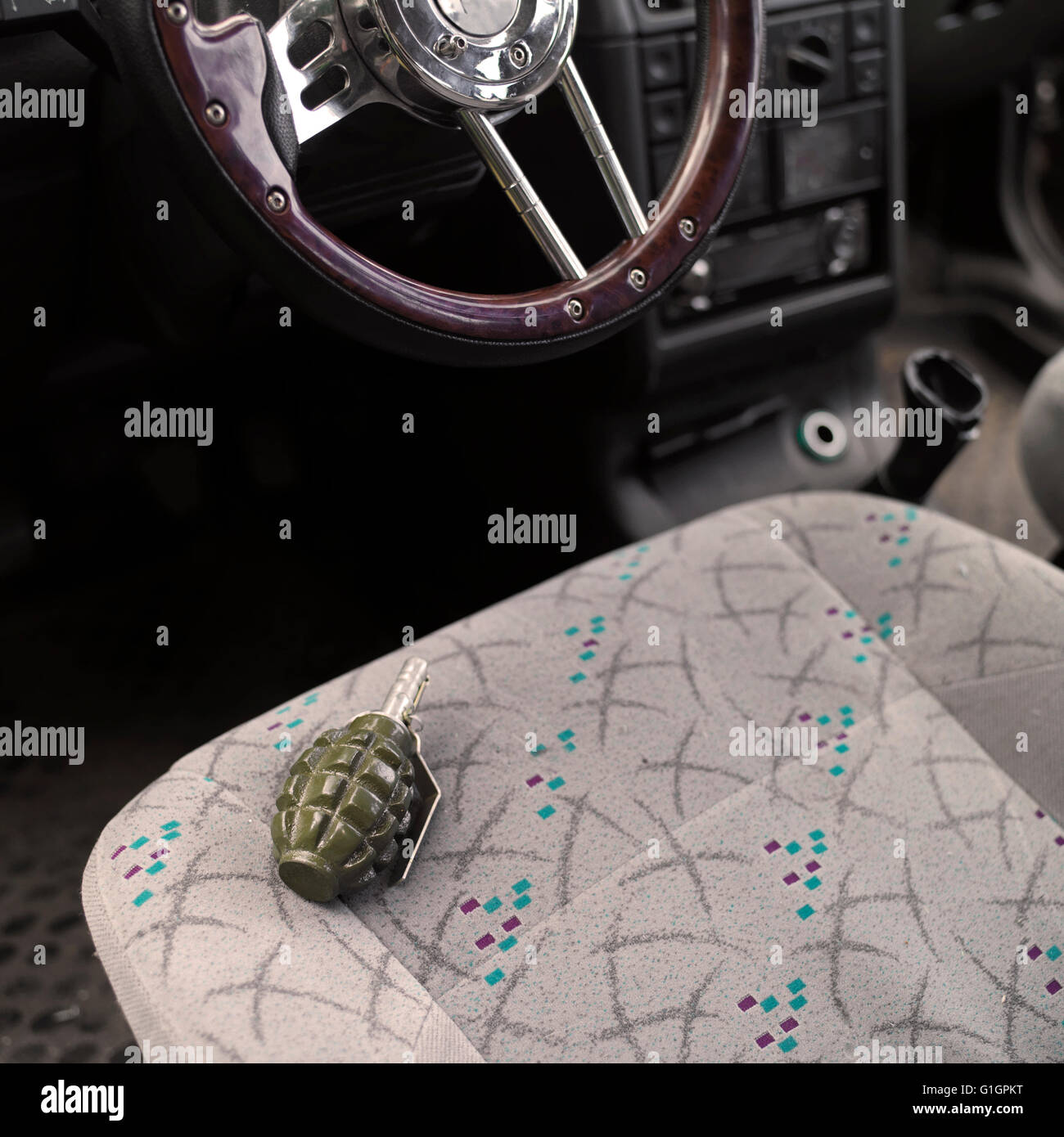Hand grenade on a car front seat, selective color shot, concept of ...