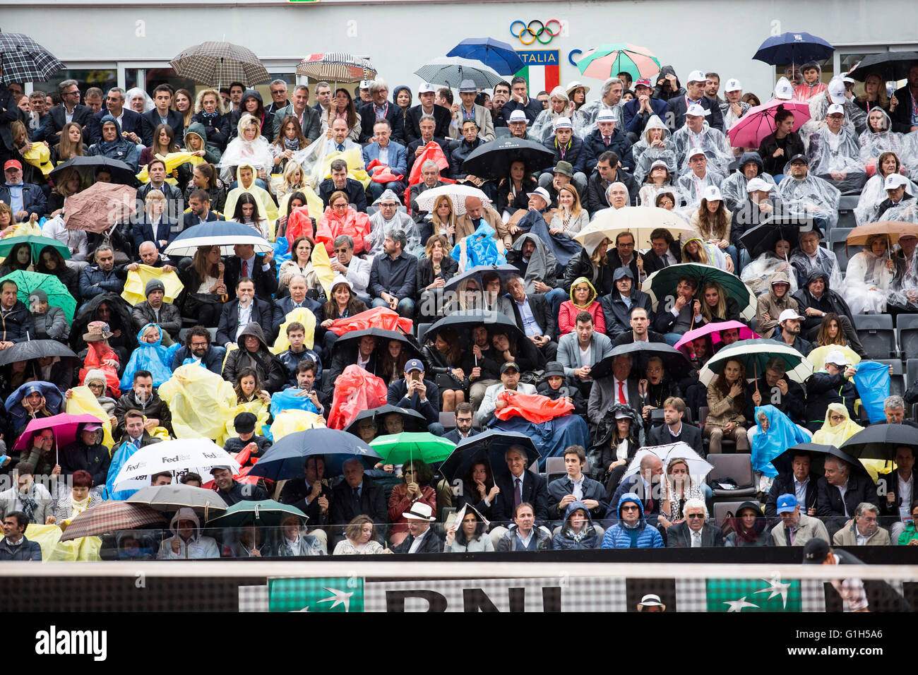 Crowd of spectators watching tennis in the rain with umbrellas in Rome ...