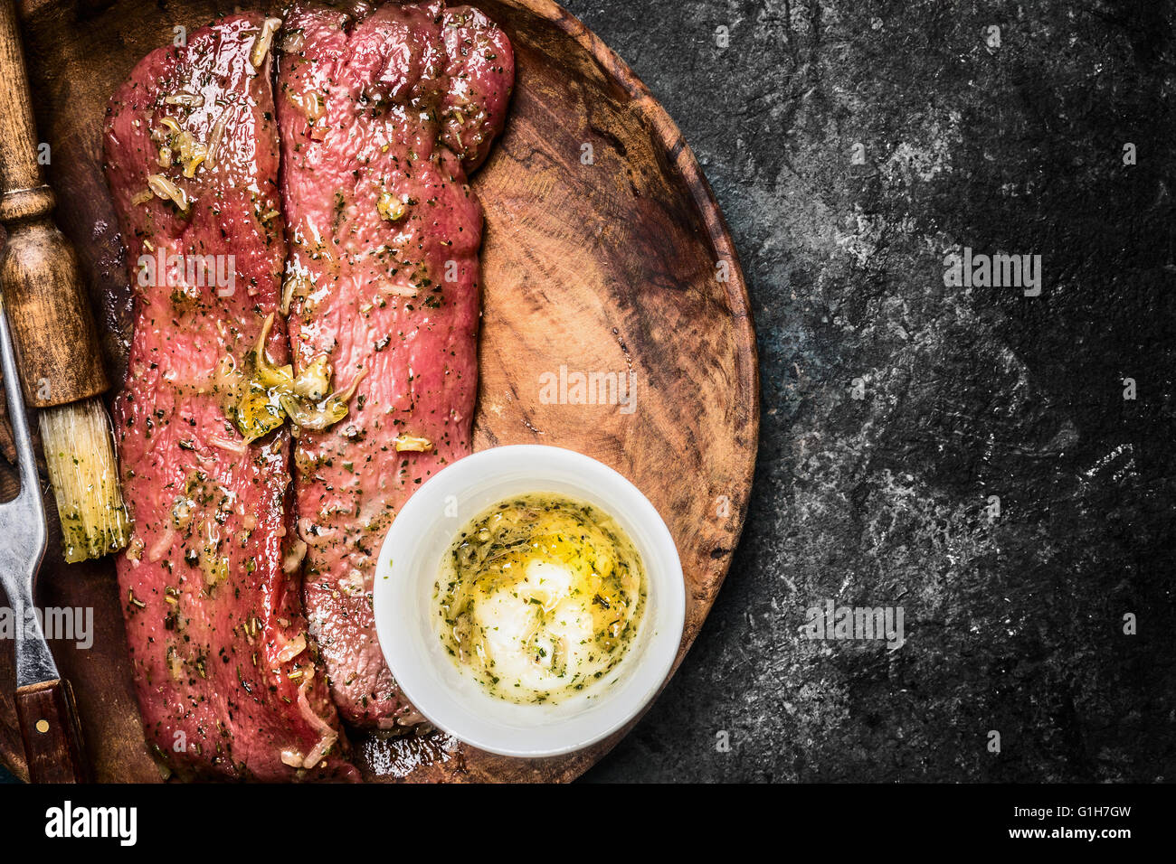 Meat fillet with oil marinade and brush on dark rustic background, top ...
