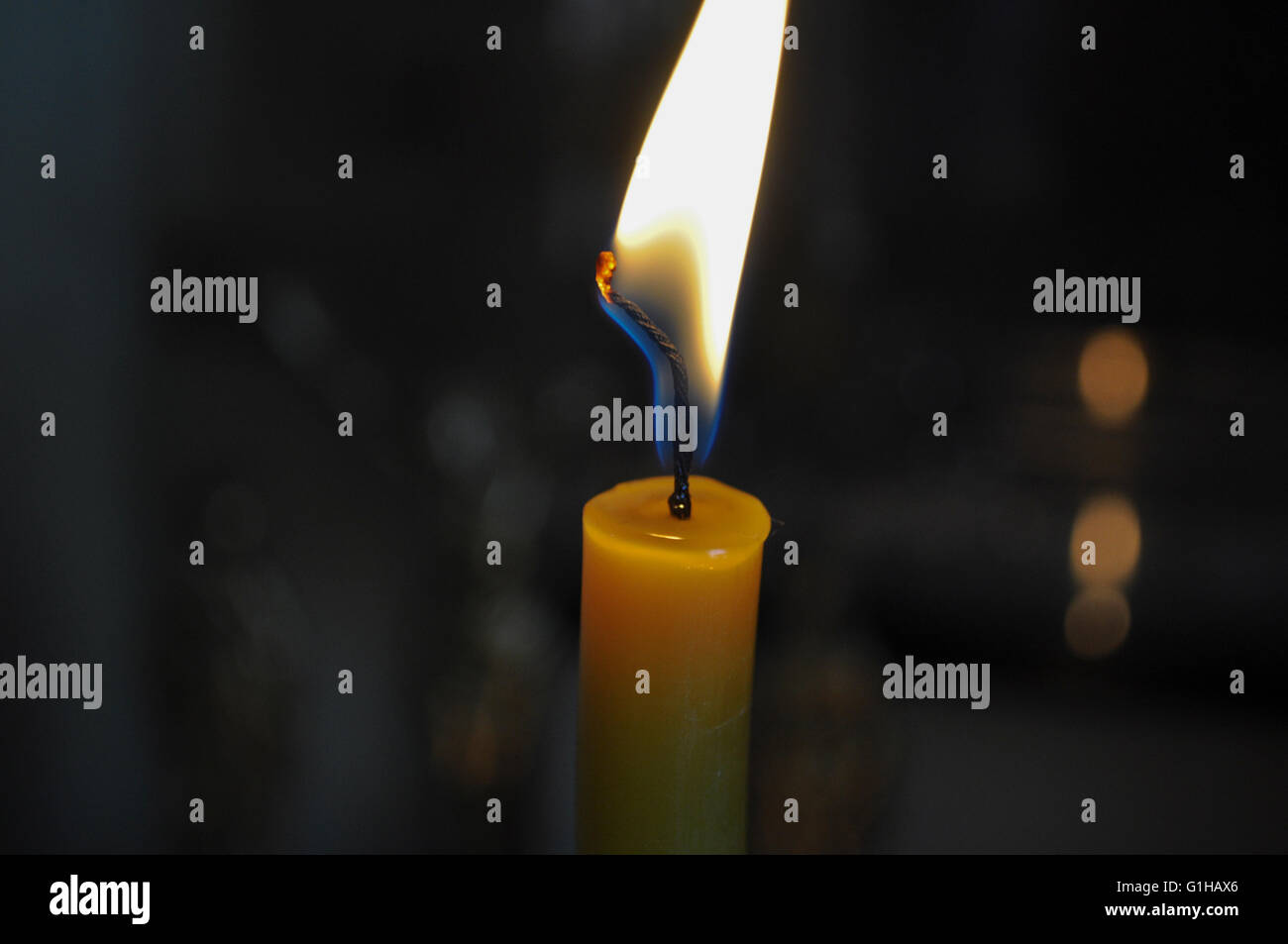 yellow candle burning with a bright flame in the dark Stock Photo - Alamy