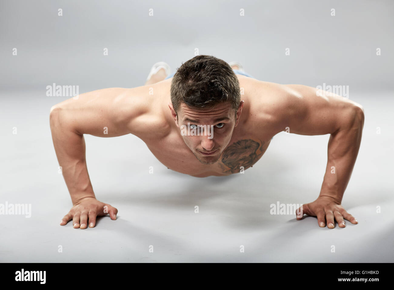Fitness model doing pushups on gray background in studio Stock Photo ...