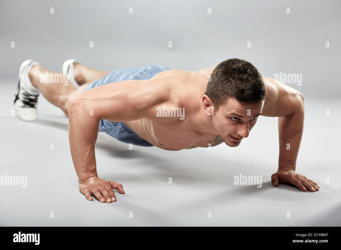 Fitness model doing pushups on gray background in studio Stock Photo ...
