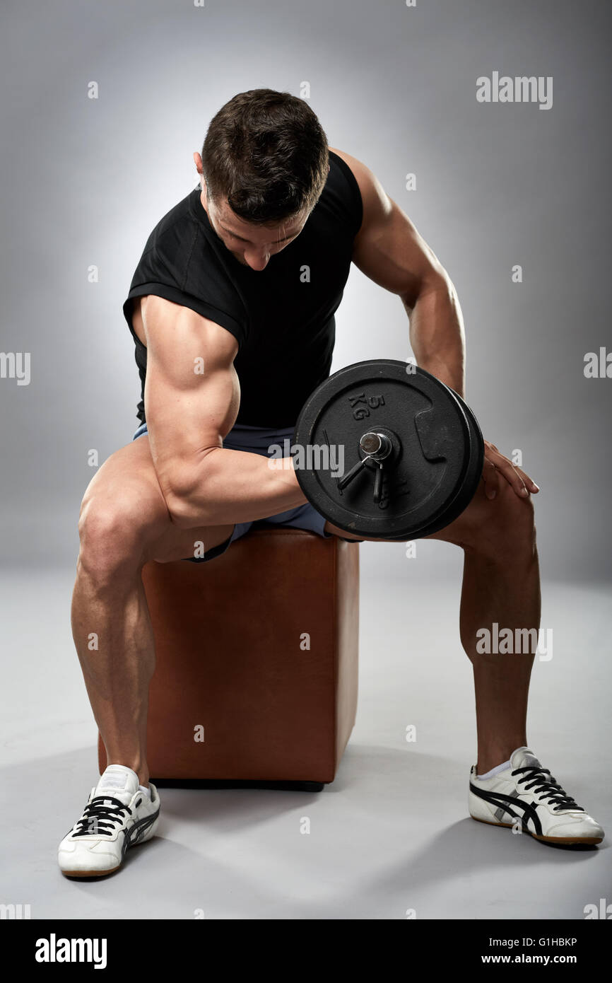 Man doing biceps curl in seated position, studio shot Stock Photo - Alamy