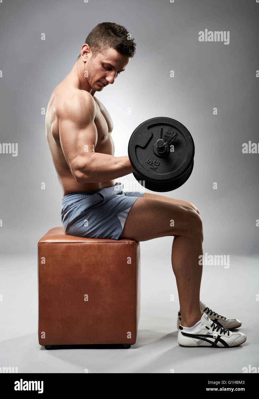 Man doing biceps curl in seated position, studio shot Stock Photo - Alamy