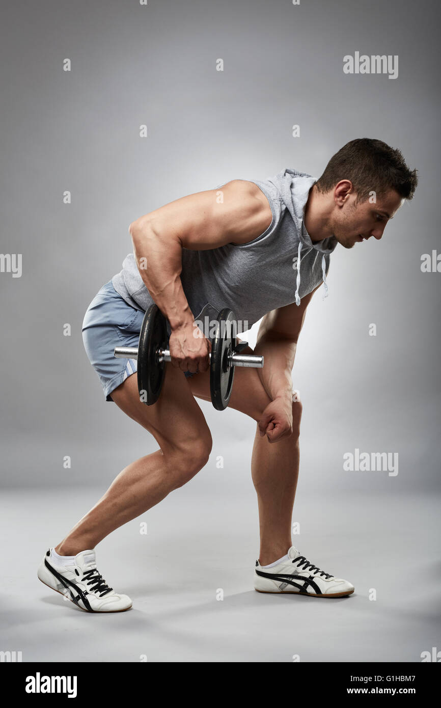 Man doing dumbbell row over gray background in studio Stock Photo - Alamy