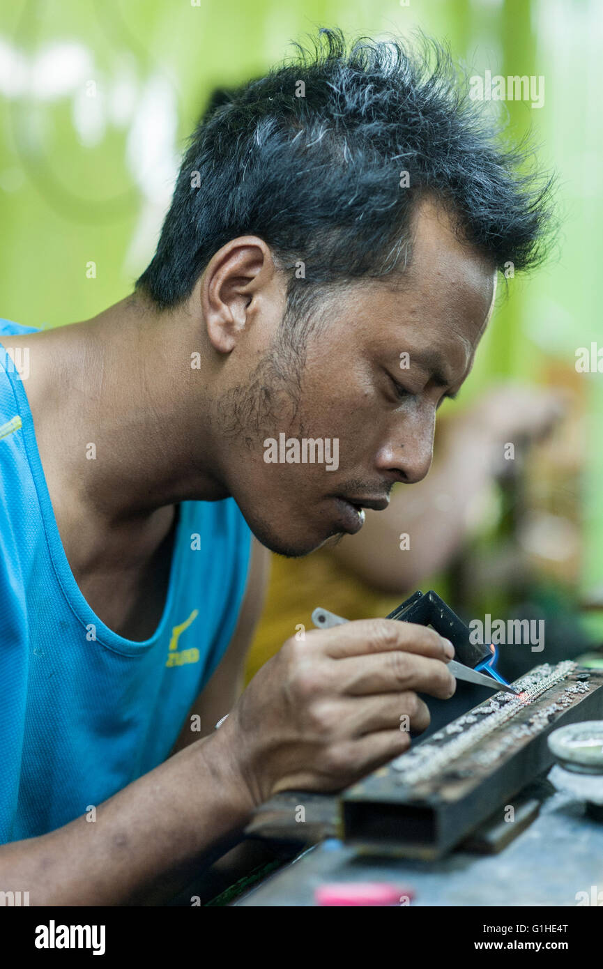 A young Burmese man making silver jewelry in a silver workshop on Inle ...