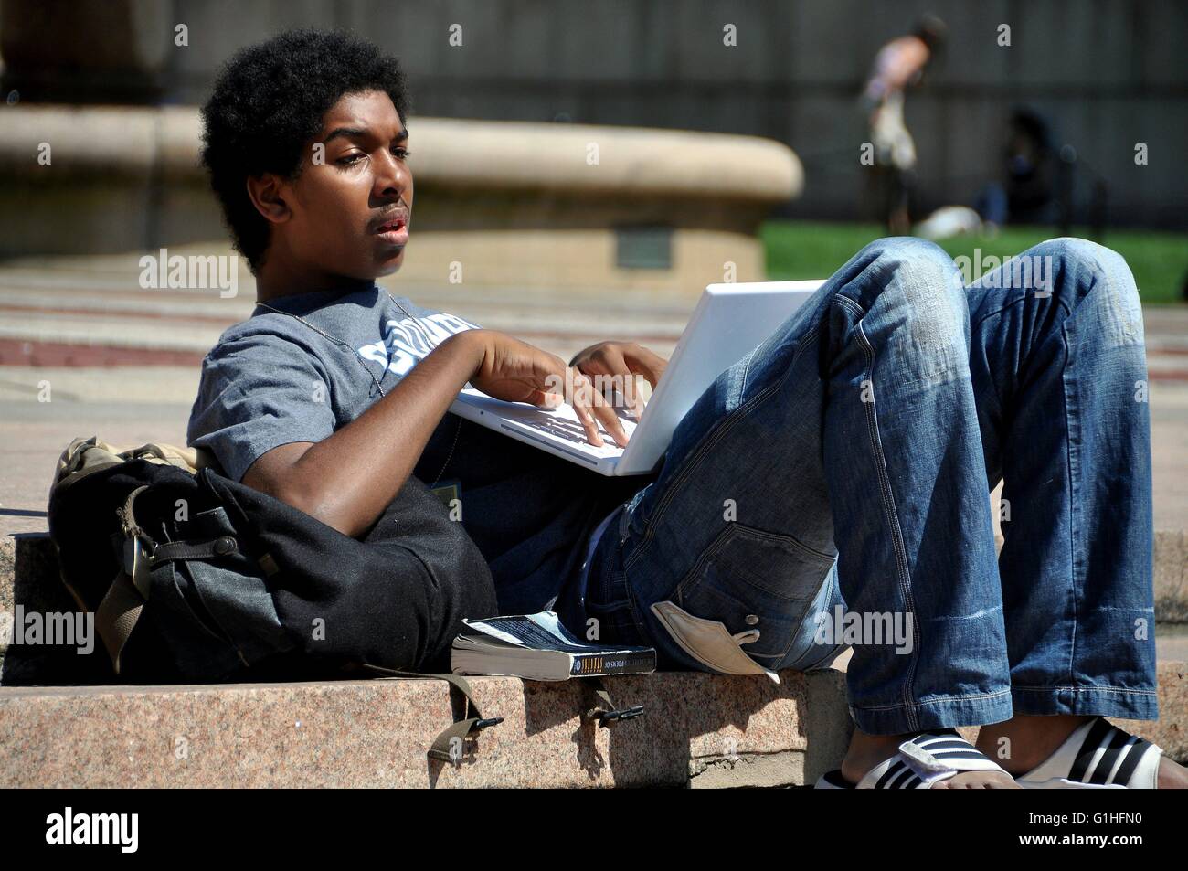 New York City: Student using his laptop computer sitting on the steps ...