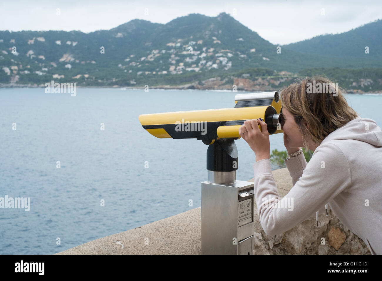 Young woman looking through coin-operated tourist telescope Stock Photo ...