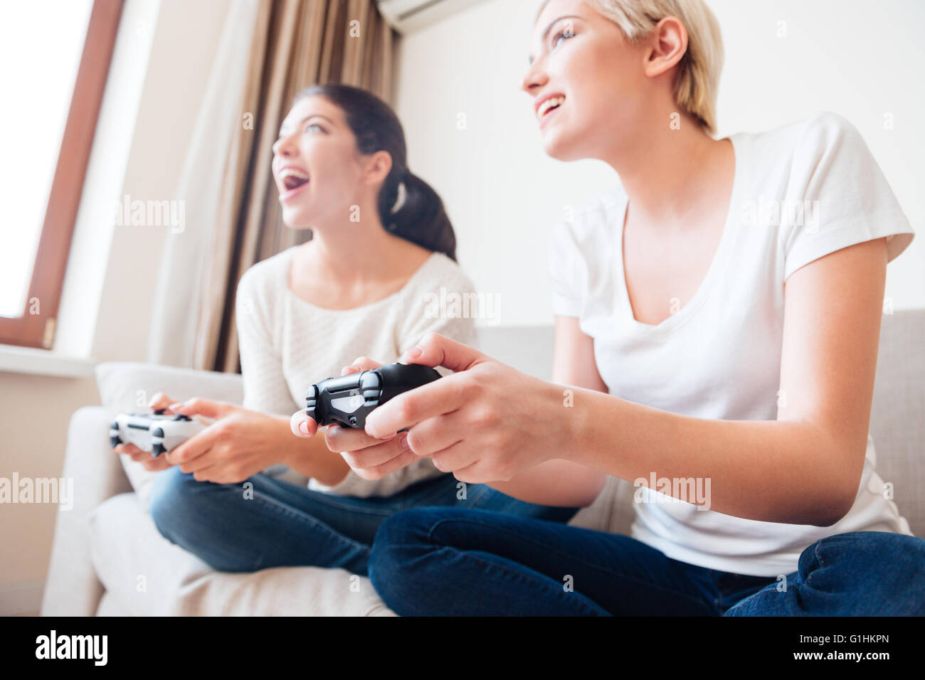 Two cheerful girlfriends playing video games Stock Photo - Alamy
