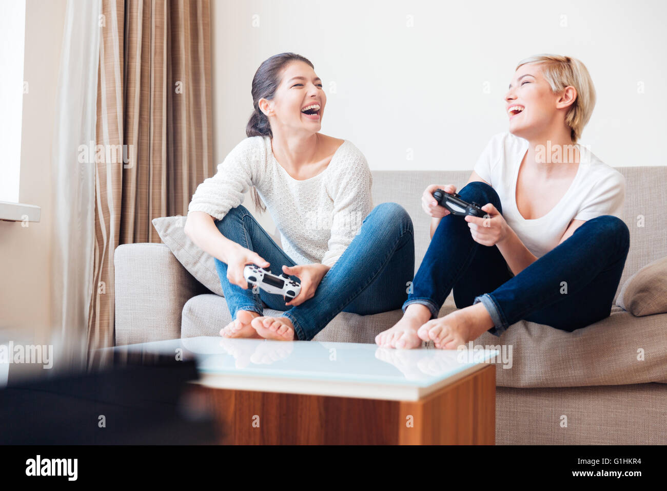 Two laughing girlfriends playing video games with joystick Stock Photo ...