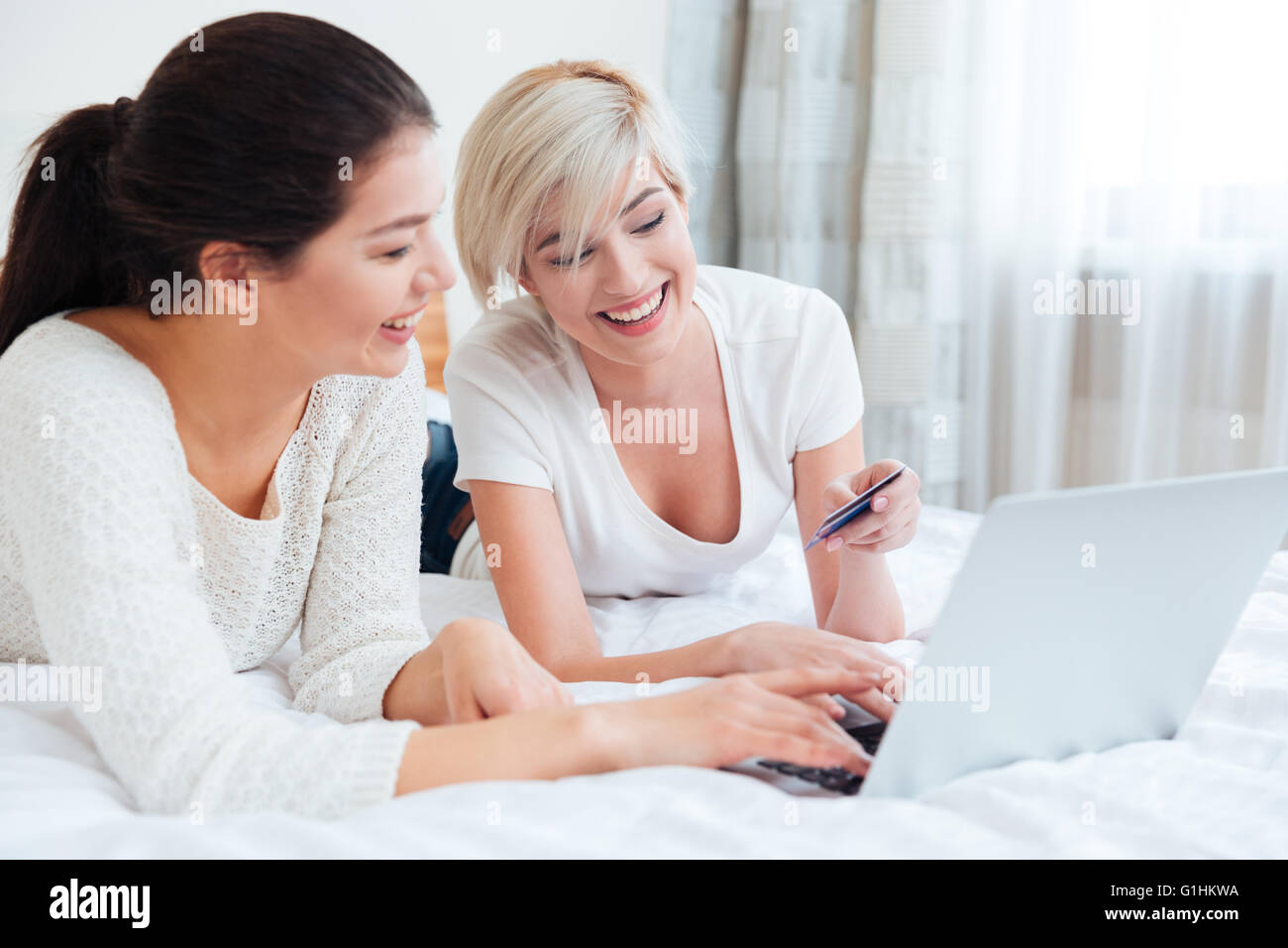 Two happy women shopping online on the laptop computer at home Stock ...