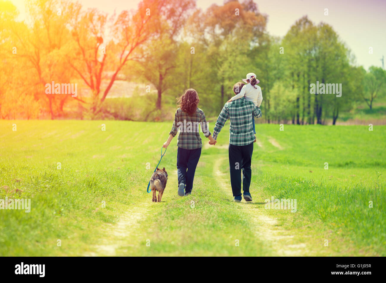 Happy family with dog walking on the rural dirt road. Little girl ...