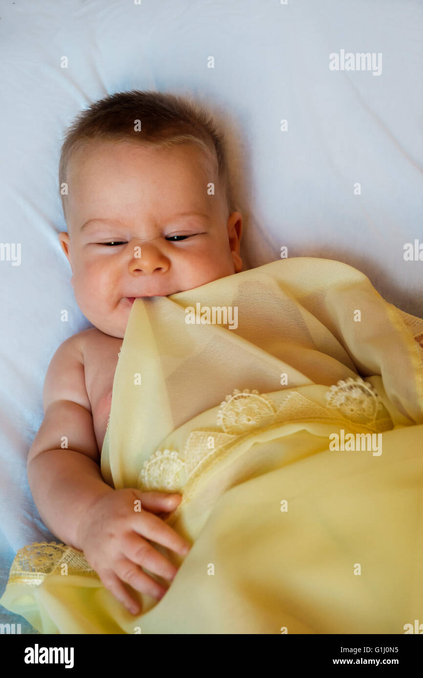 Baby in yellow blanket on a white background Stock Photo - Alamy
