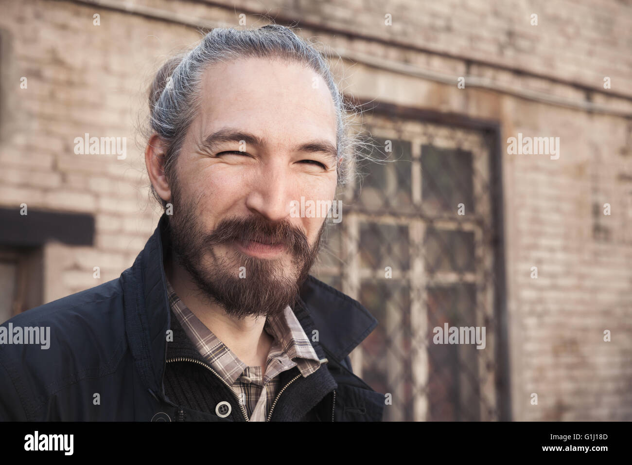 Outdoor portrait of young bearded Asian man in black on urban grungy ...