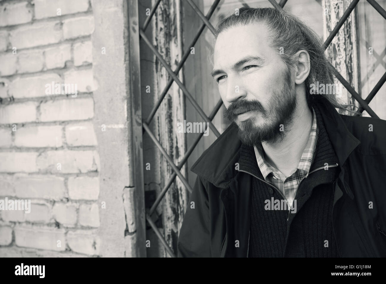Outdoor portrait of young bearded Asian man in black on gray urban ...