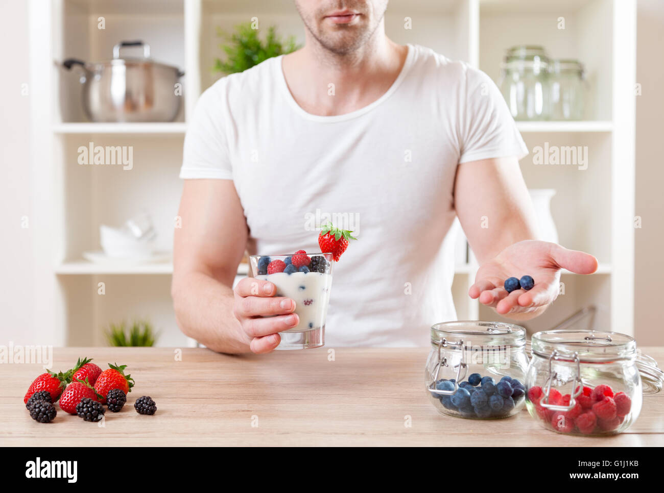 Healthy eating concept. Man with delicious yogurt with fresh berries ...