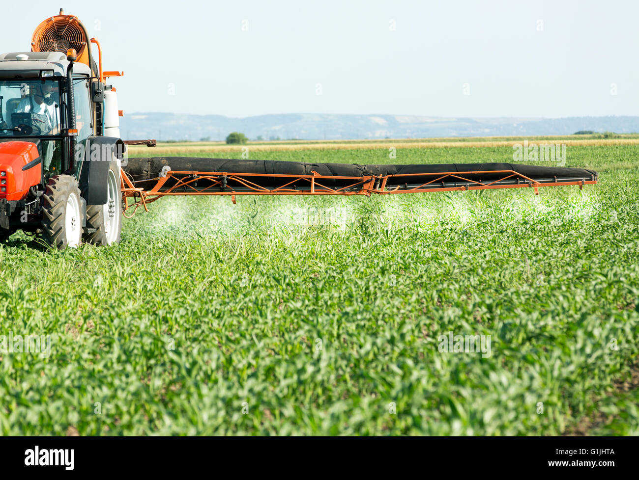 Farmer in red tractor spraying soybean field with herbicides ...