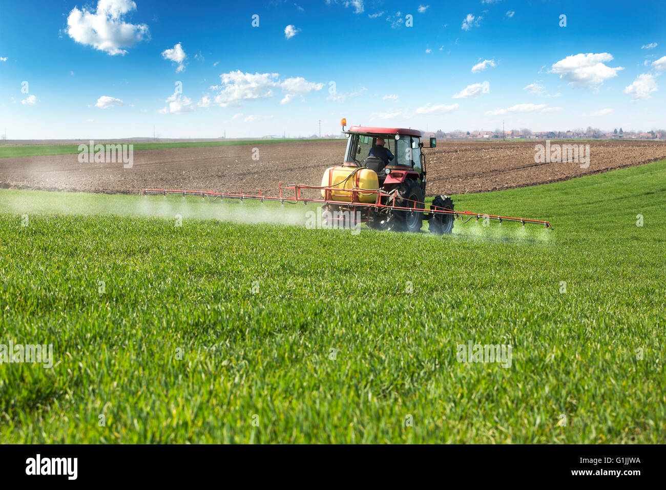 Farmer spraying wheat field with tractor sprayer at spring season Stock ...