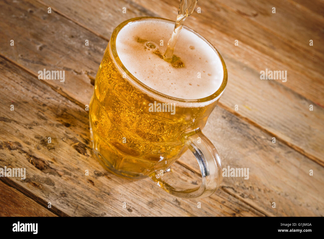 Traditional stein with lager on a rustic wooden table Stock Photo - Alamy