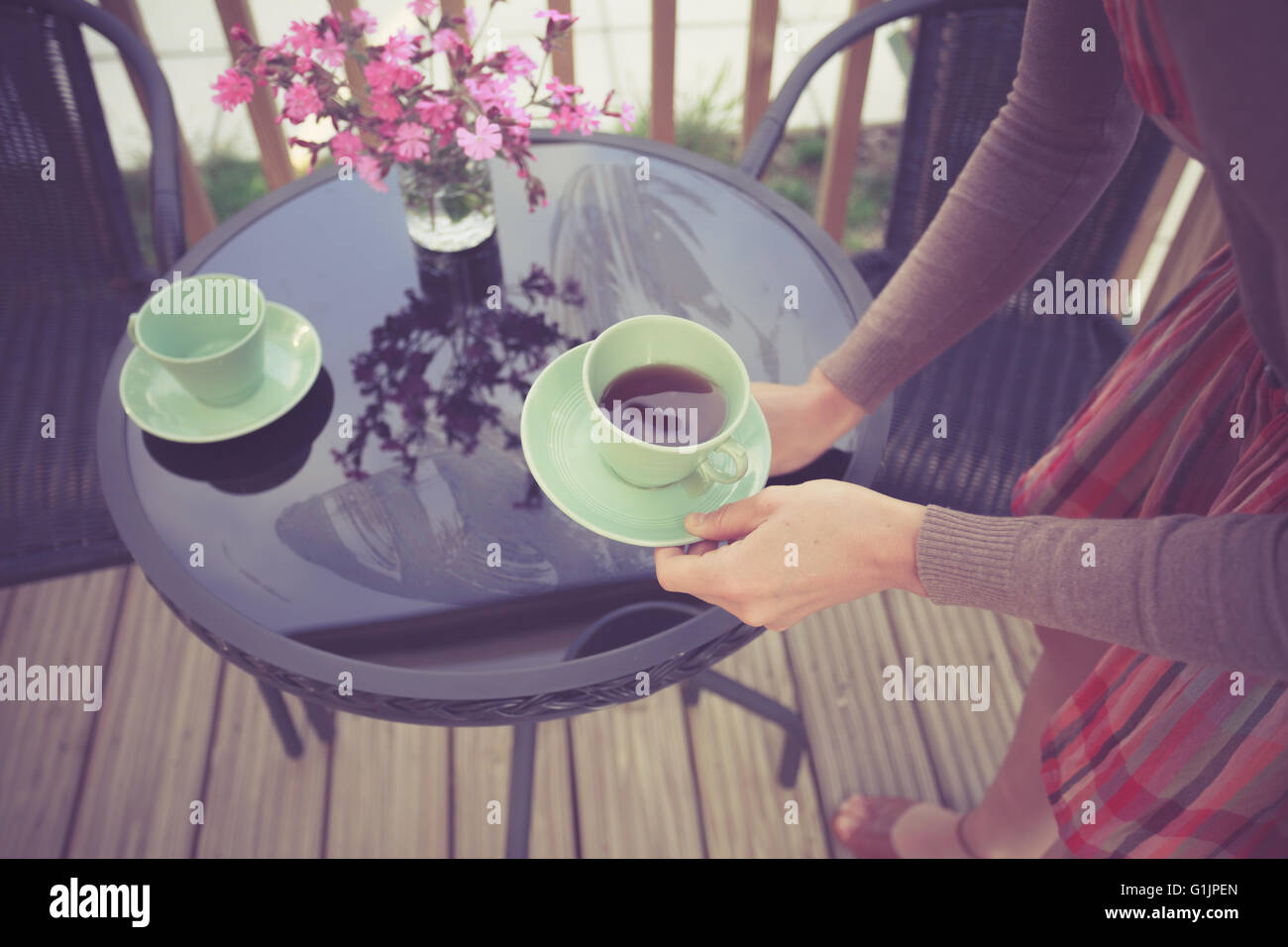 A young woman is setting the table for tea outside on the porch Stock ...