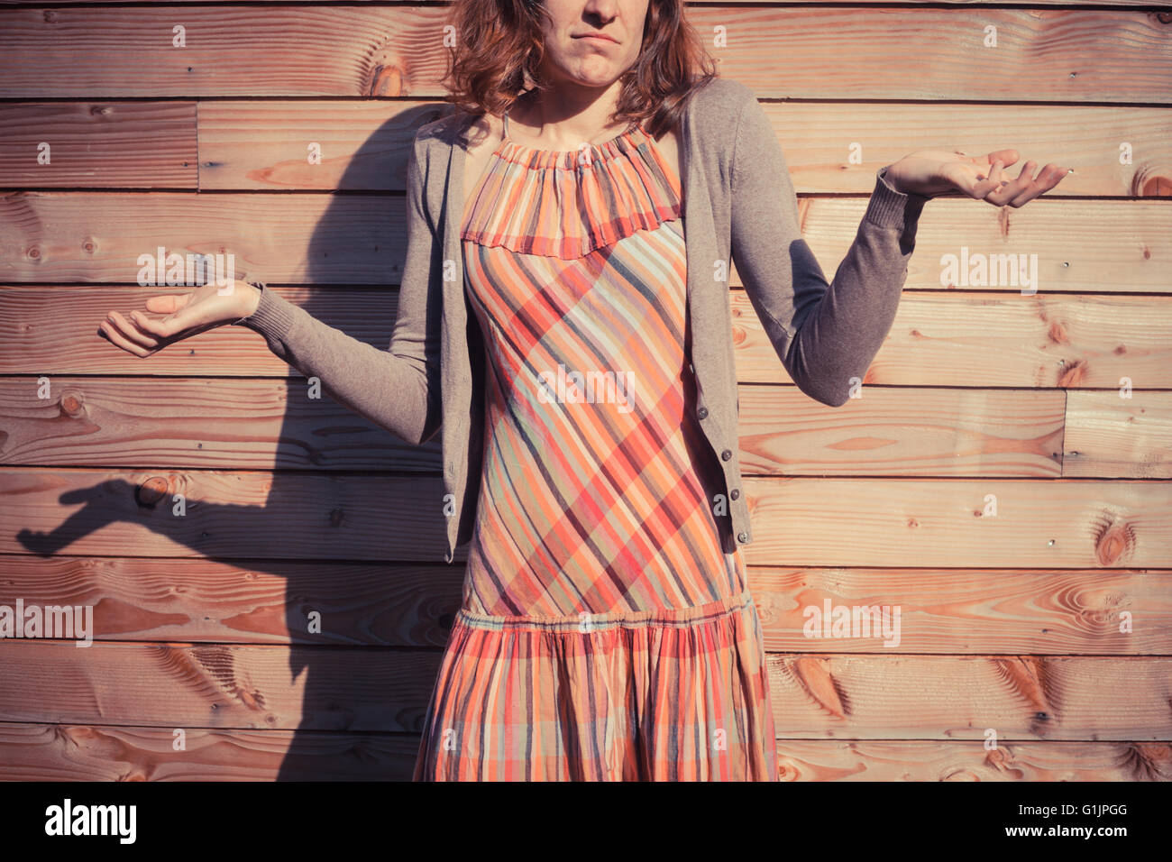 A confused young woman standing outside a wooden cabin Stock Photo - Alamy