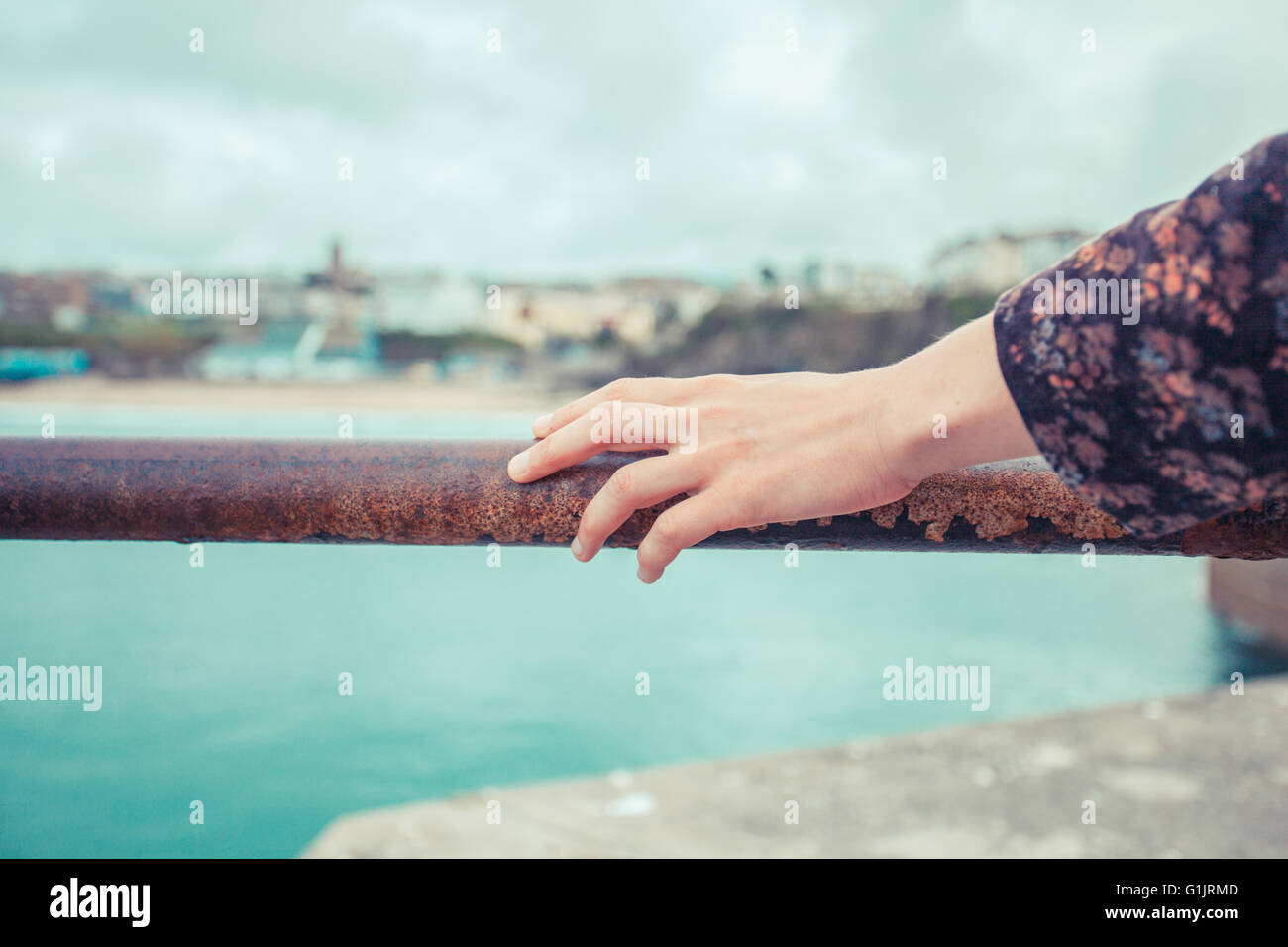 A young woman is resting her hand on a rail in the harbour Stock Photo ...
