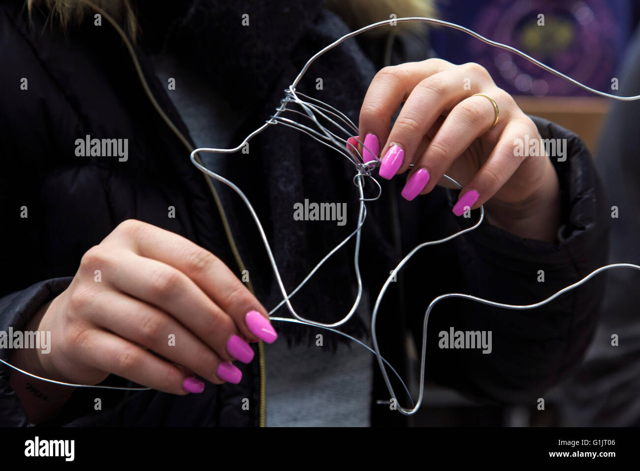 Hands with pink nails bend a wire Stock Photo - Alamy