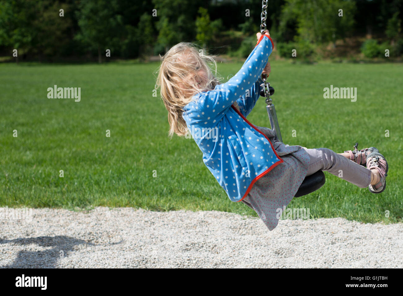 Happy Child blond girl (age 5) rids on Flying Fox play equipment in a ...