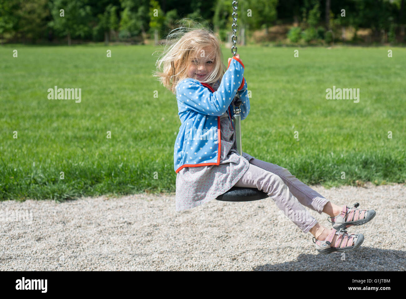 Happy Child blond girl (age 5) rids on Flying Fox play equipment in a ...