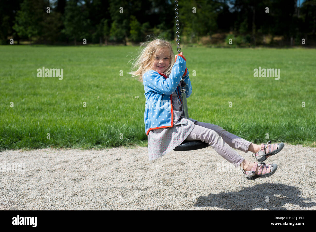 Happy Child blond girl (age 5) rids on Flying Fox play equipment in a ...