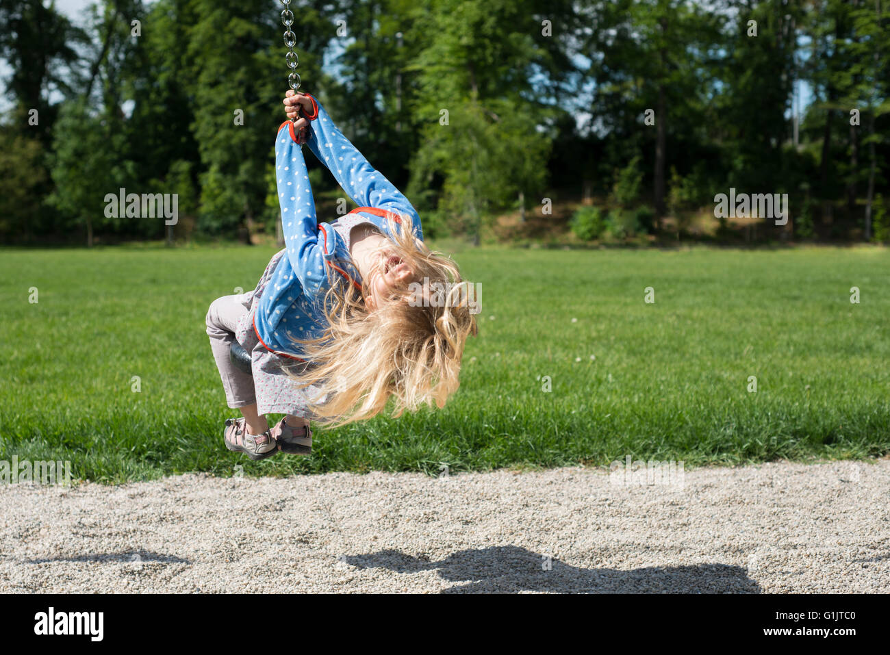 Happy Child blond girl (age 5) rids on Flying Fox play equipment in a ...