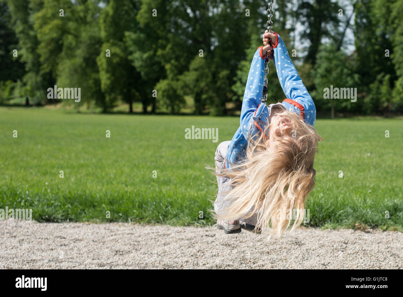 Happy Child blond girl (age 5) rids on Flying Fox play equipment in a ...